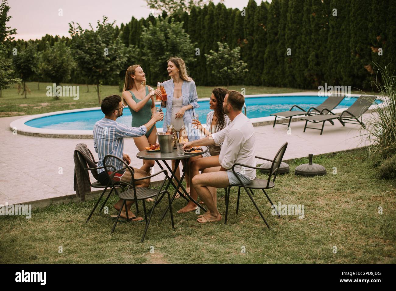 Group of happy young people cheering with cider by the pool in the ...