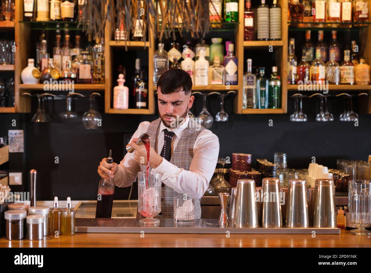 Young mixologist making a special cocktail for his clients in a bar ...
