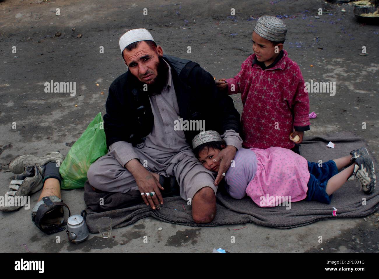 A disabled Afghan man begs with his children in Kabul, Afghanistan on ...