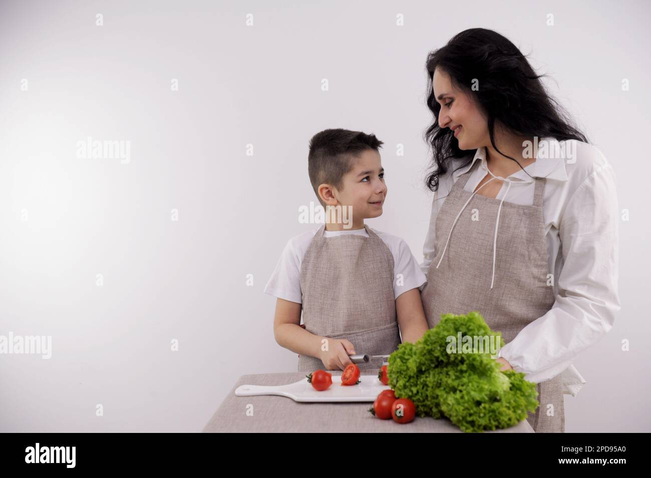 Mom and son cook food in the kitchen together. An adult boy helps mom ...