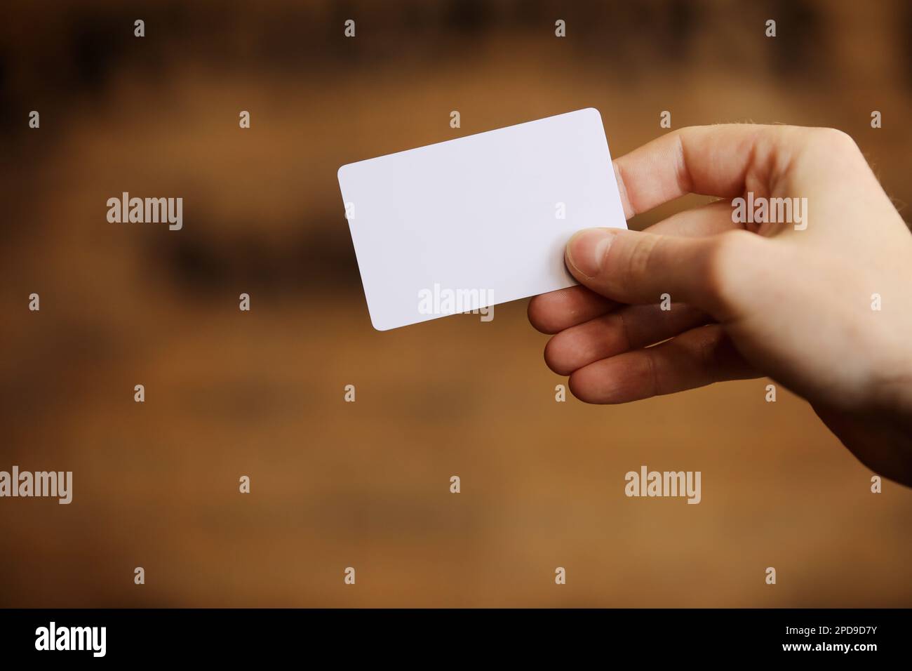 Male hand holds blank white card mockup on brick wall background. Plain ...