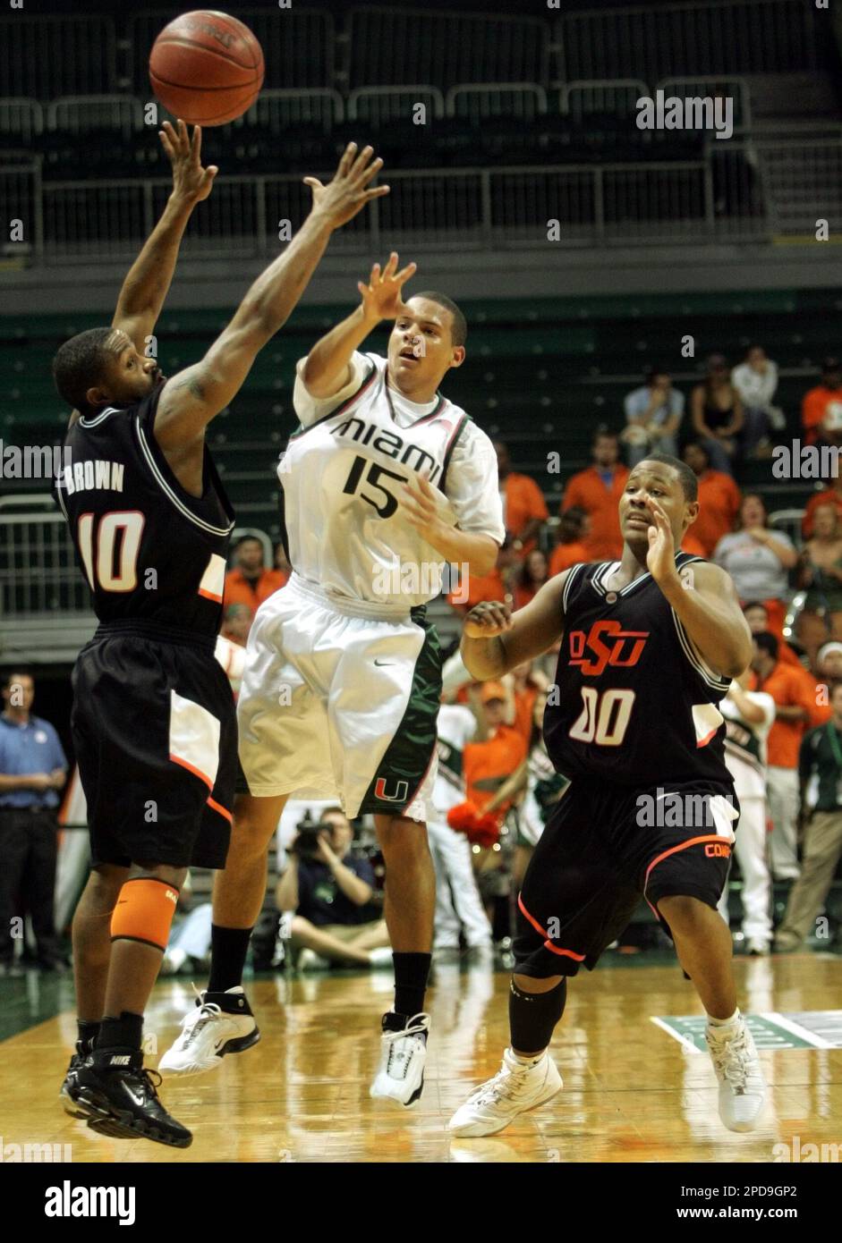 Miami guard Denis Clemente passes past Oklahoma State guards Jamaal ...