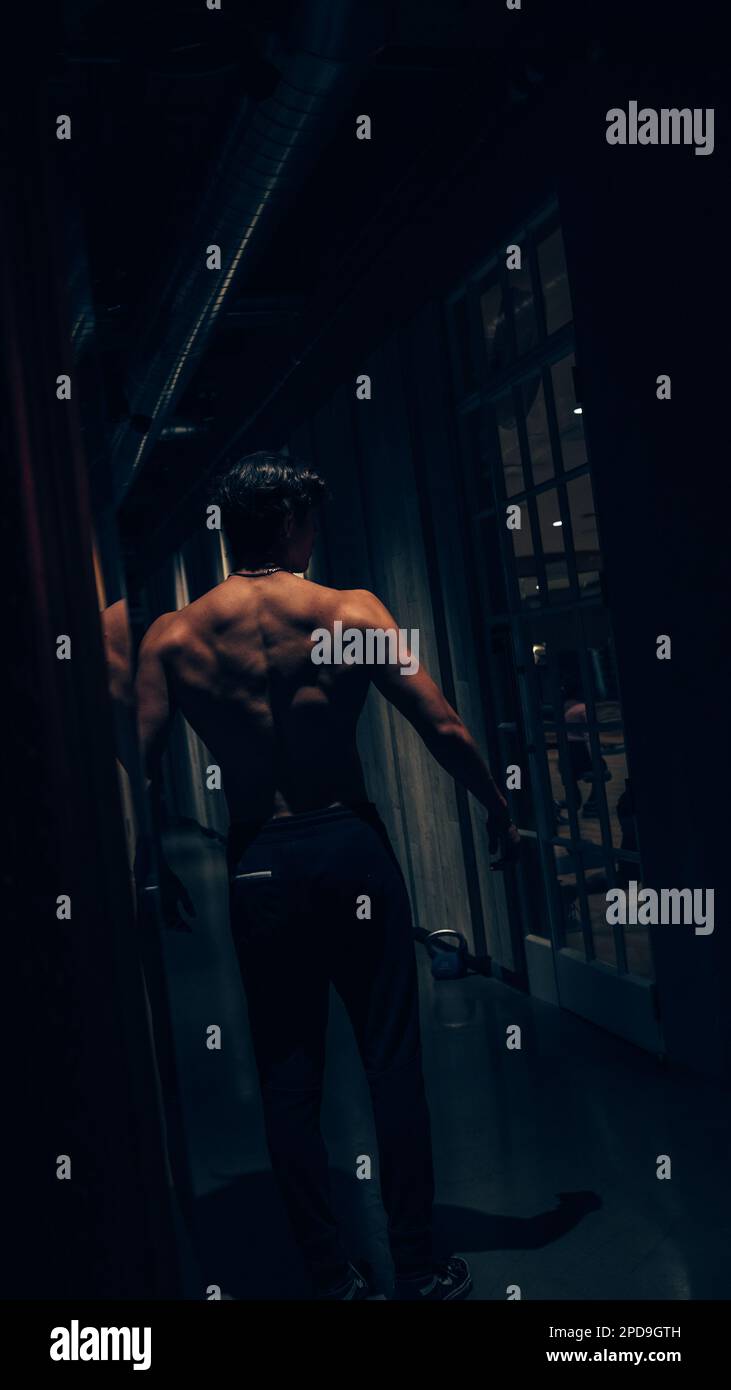 A man is performing pull-ups in a dimly lit gym filled with weight ...