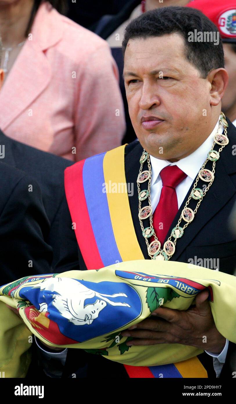 Venezuela's President Hugo Chavez holds the new national flag with an ...