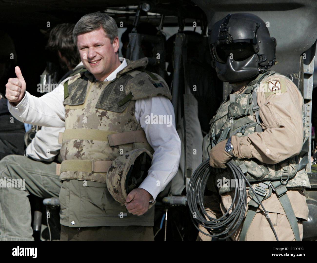 Prime Minister Stephen Harper, wearing body armour, gives a thumbs-up ...