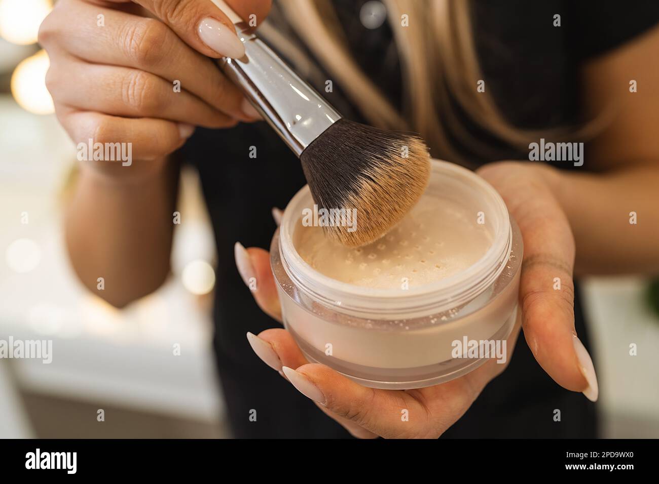 Makeup artist holding powder can with brush for powdering a customer at ...