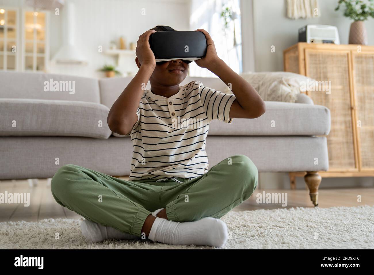 African American boy child sitting on floor at home using virtual ...