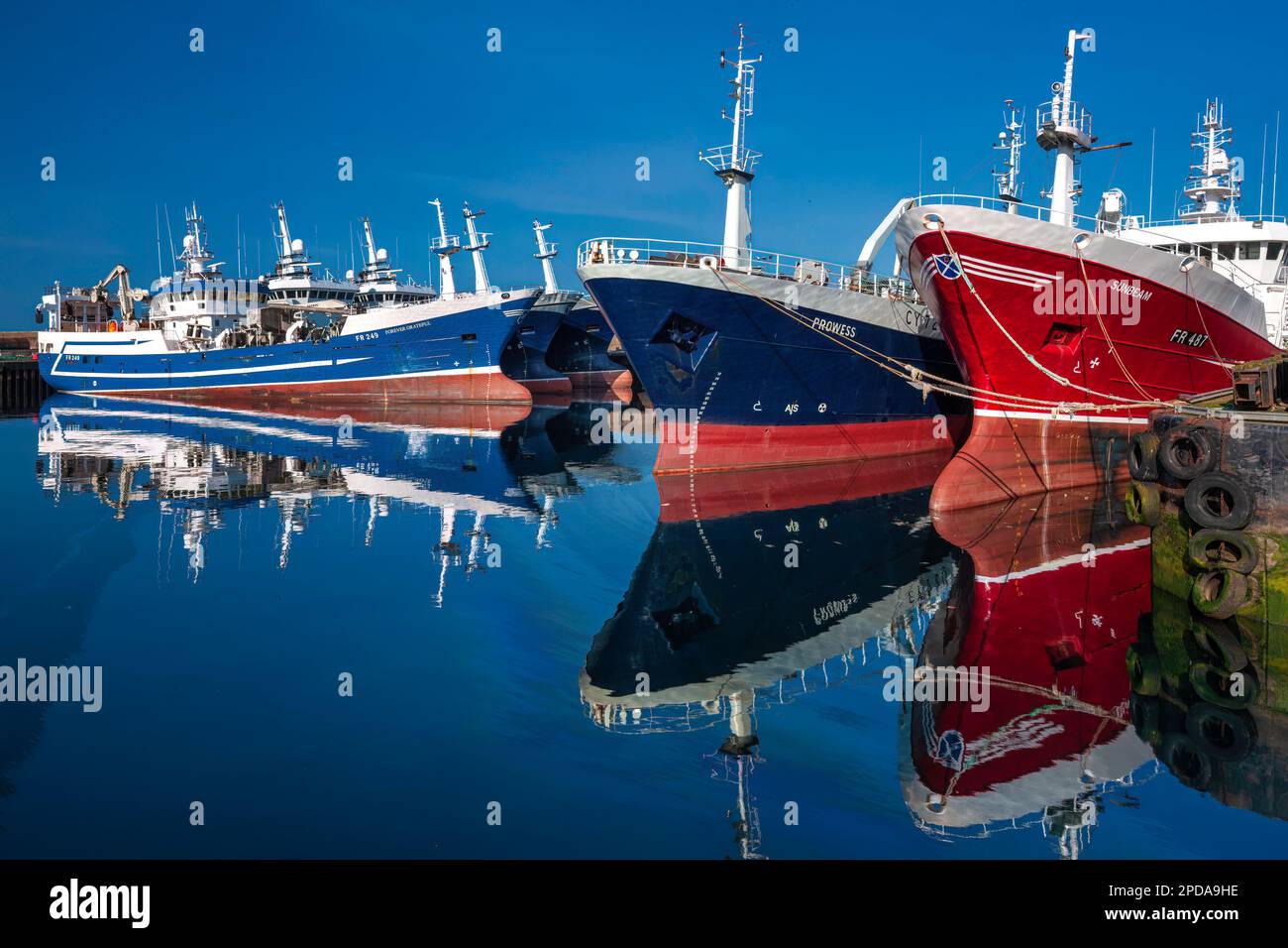 Fishing boats reflected in the water at Fraserburgh Harbour ...