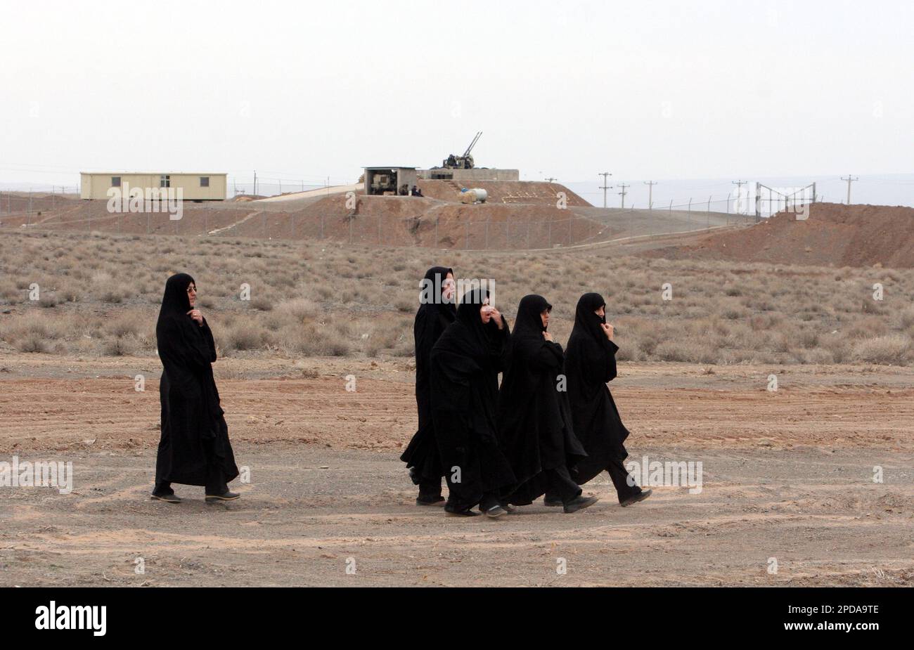 In front of an anti-aircraft gun, Iranian women make their way at the ...