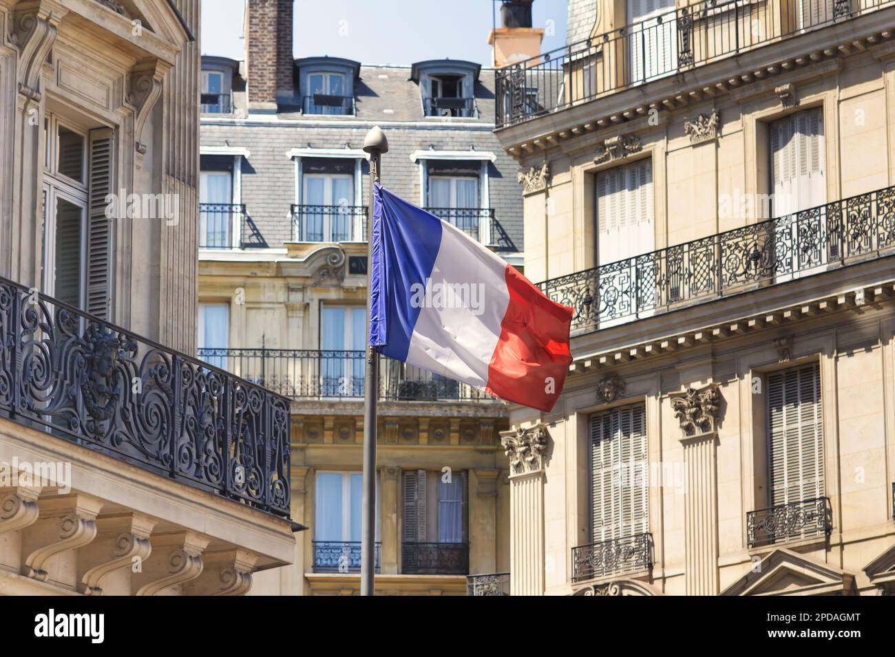 French national flag waving in Paris, the capital of France with residential houses in ...