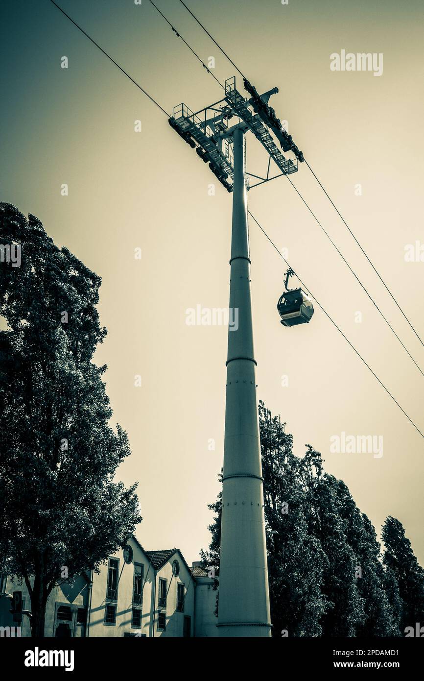 Split toned image of cable car and mast gliding above urban development ...