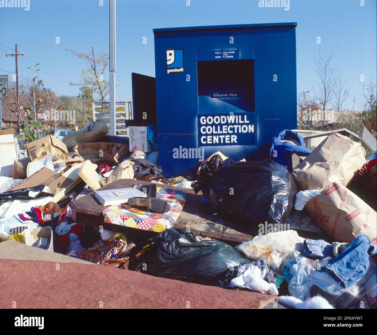 A goodwill collection center storage bin overflowing onto the pavement ...