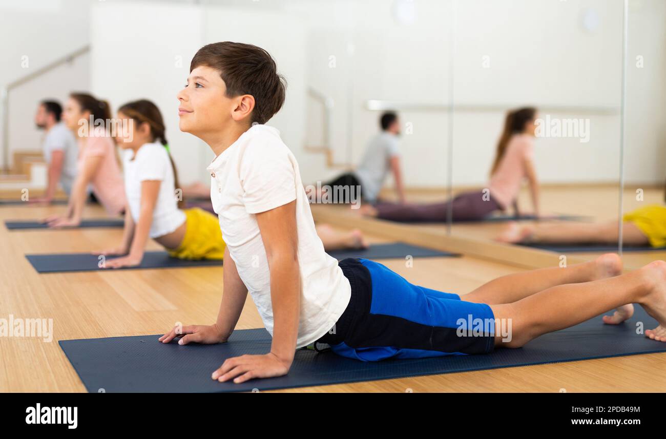 Boy doing stretching asana Bhujangasana during family yoga class Stock ...