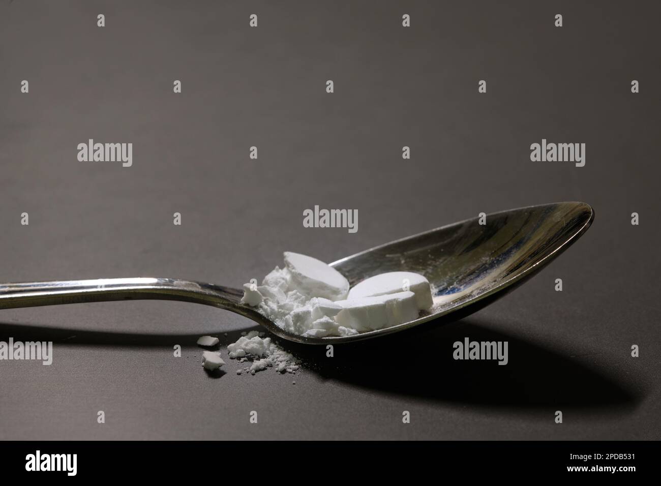 Pharmaceutical medicine drugs powder on a silver metal spoon. Smashed ...