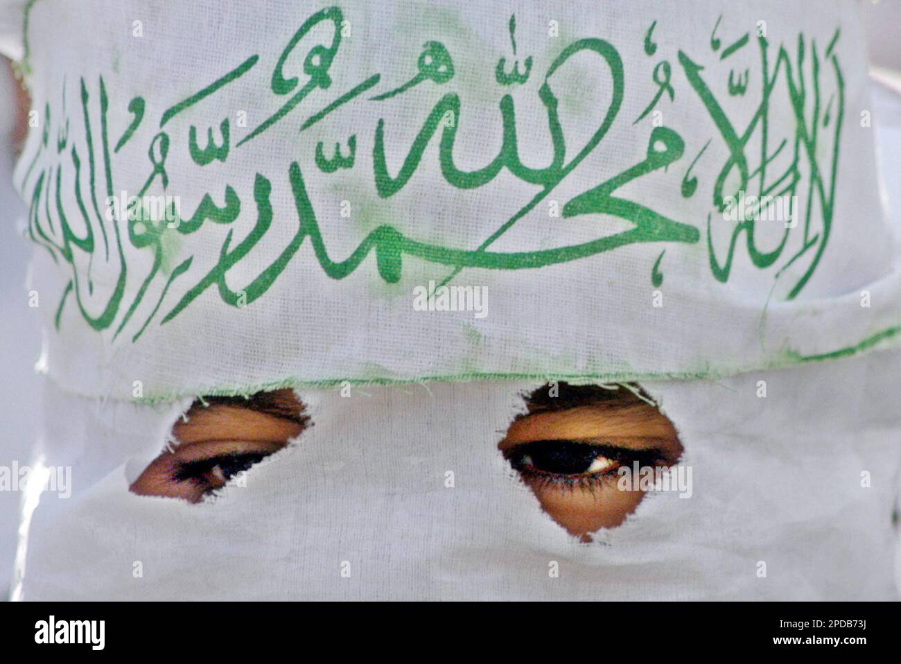 Pakistani boy, covering his face with headband thatsays "'There is no ...