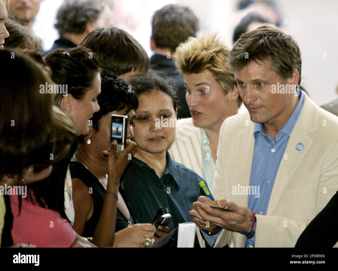 Actor Viggo Mortensen, right, signs pictures for fans as he arrives at ...