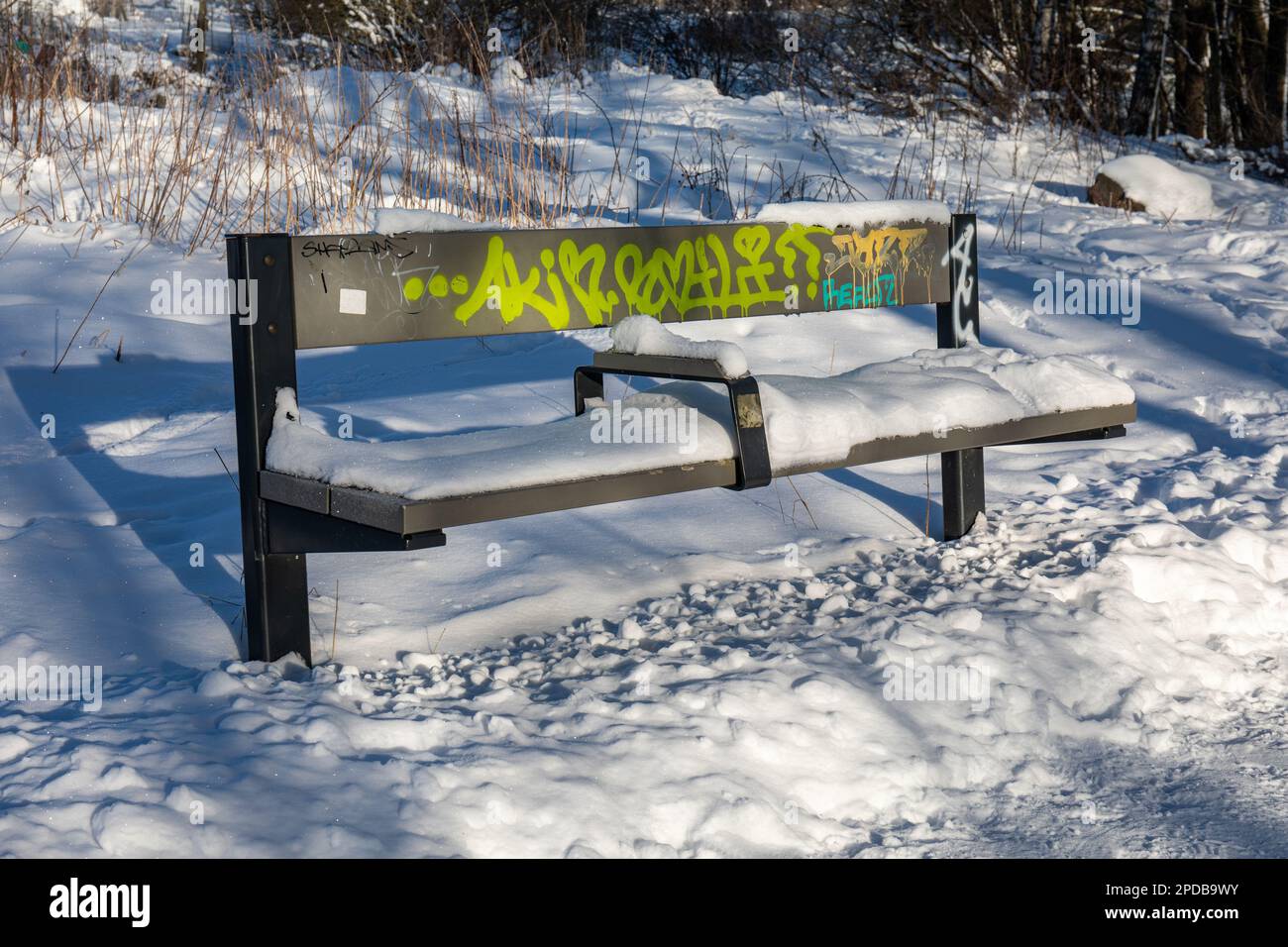 Snow and tag covered bench on a sunny winter day in Niemenmäki district ...