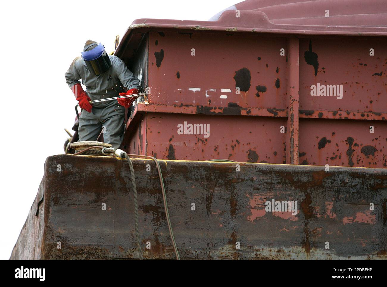 A worker use a torch to begin cutting up the barge that landed in the ...