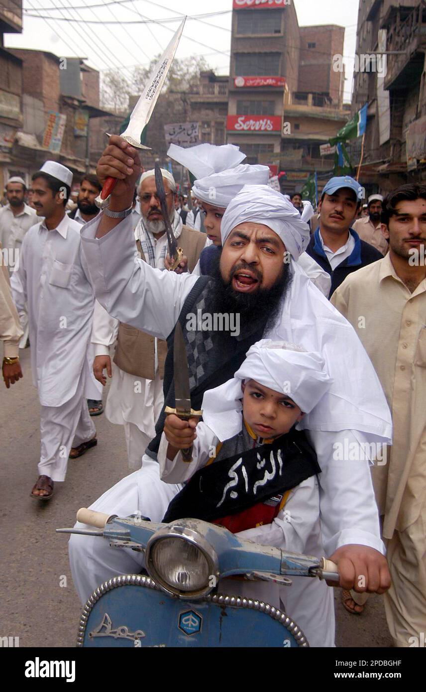 Pakistani protesters holding daggers take part in at a rally to condemn ...