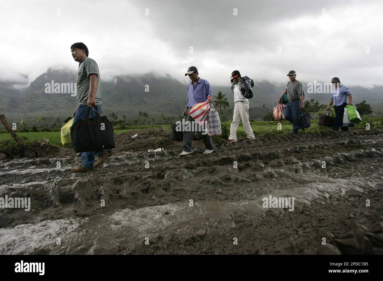 Filipino volunteers walk with their belongings through the mud of the ...