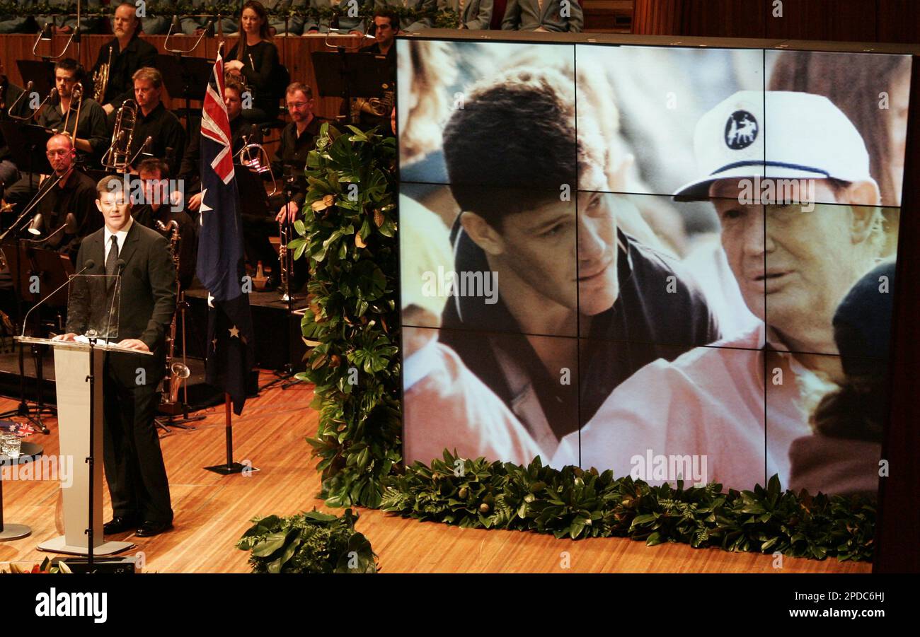 Jamie Packer stands to the left of a giant television screen with a ...