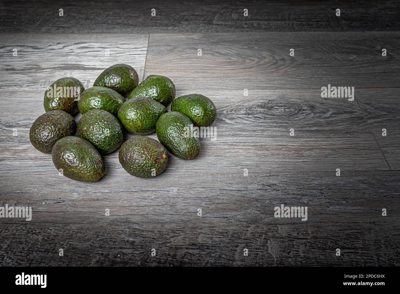 Group of Avocados on a Grey Wood Table Surface With Circle of Light on ...