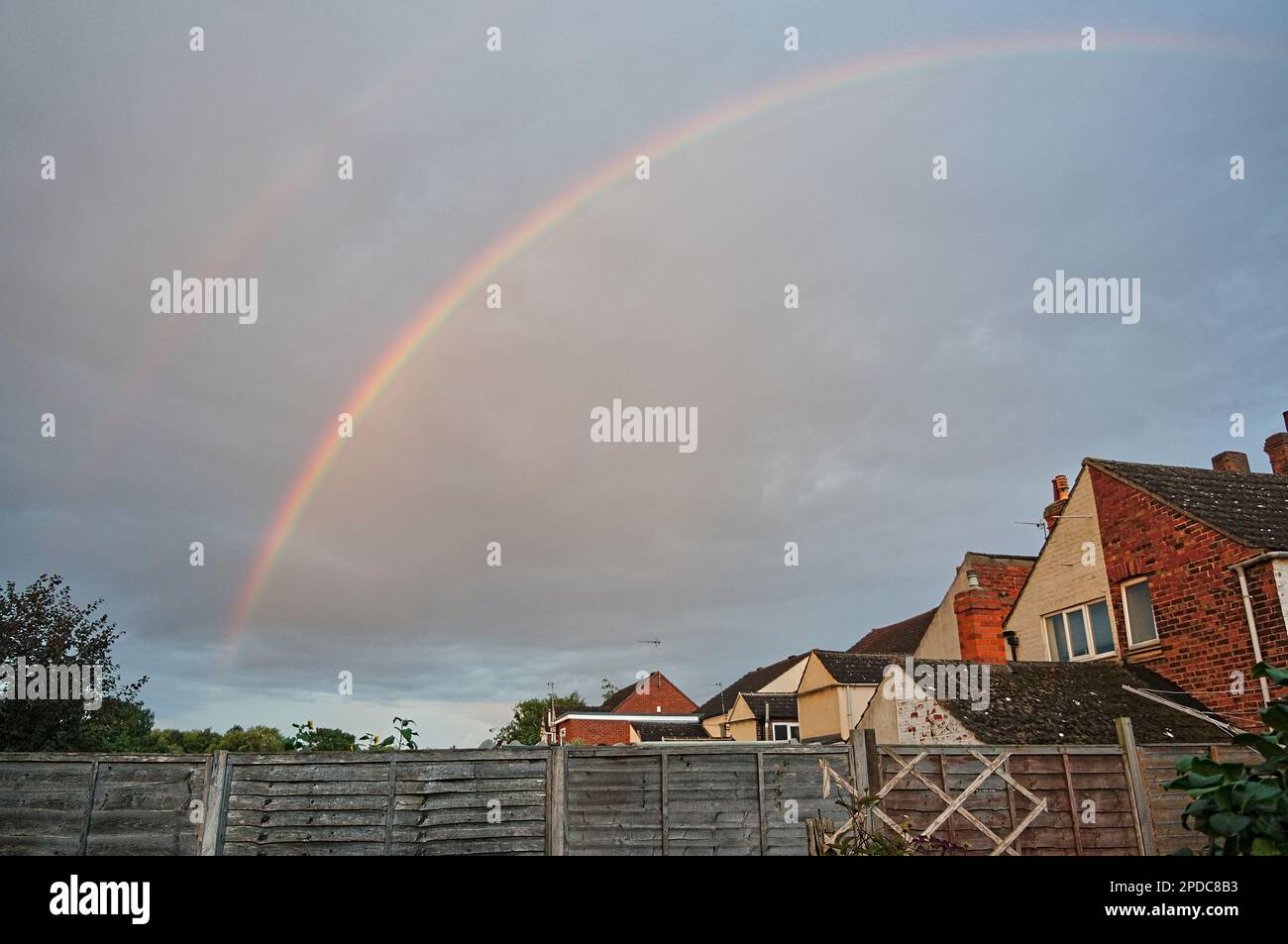 Rainbow sky with houses and garden fence below Stock Photo - Alamy