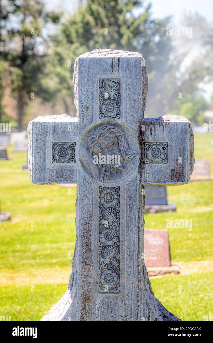 A large religious cross-shaped stone headstone with the face of Jesus ...