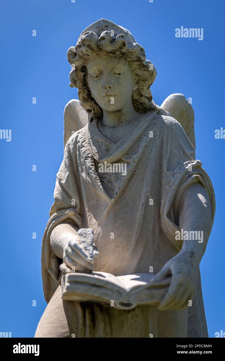 Angel stone grave marker holding a feather quill writing in a book ...
