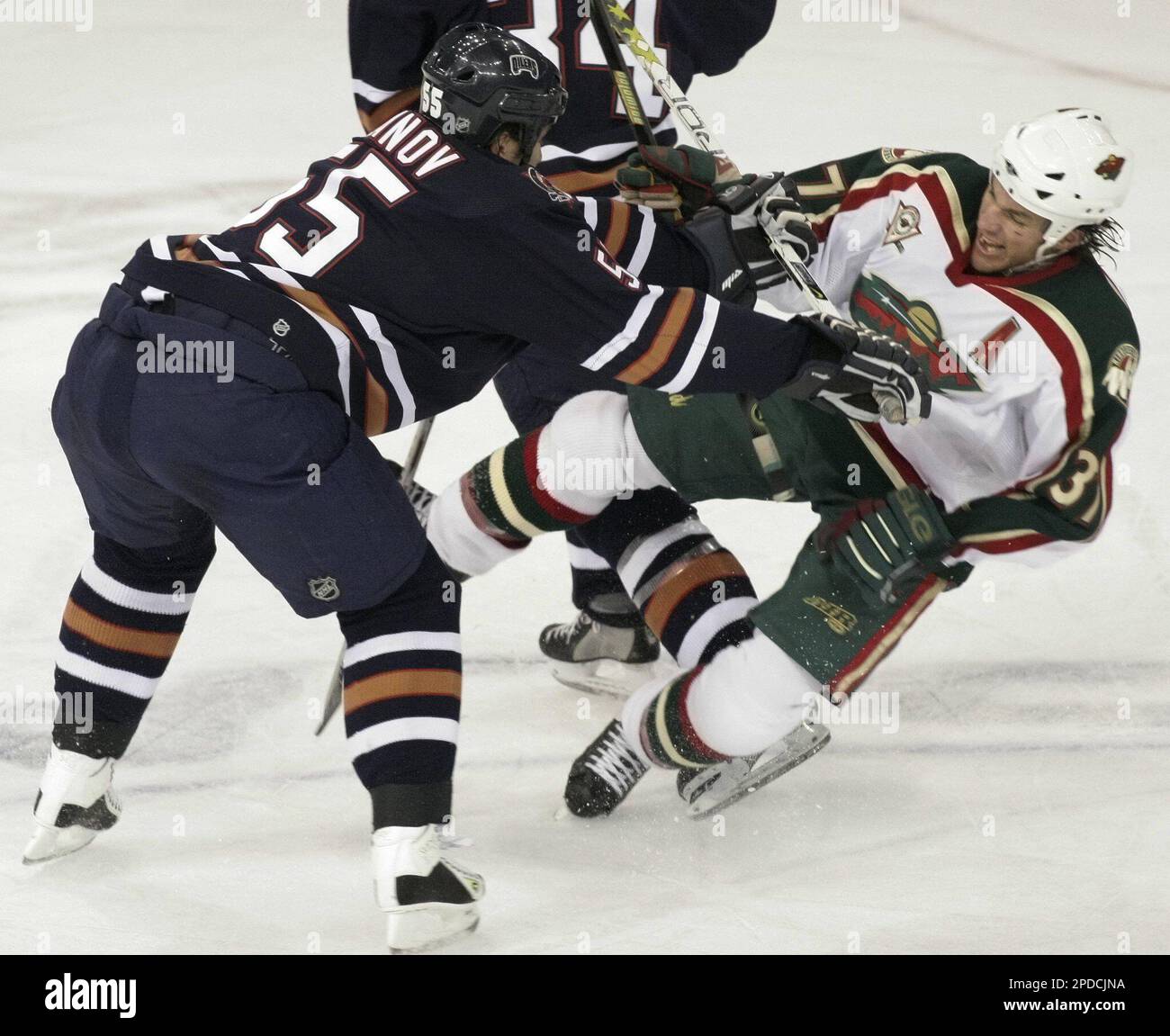 Minnesota Wild's Wes Walz, right, takes a hit from Edmonton Oilers ...