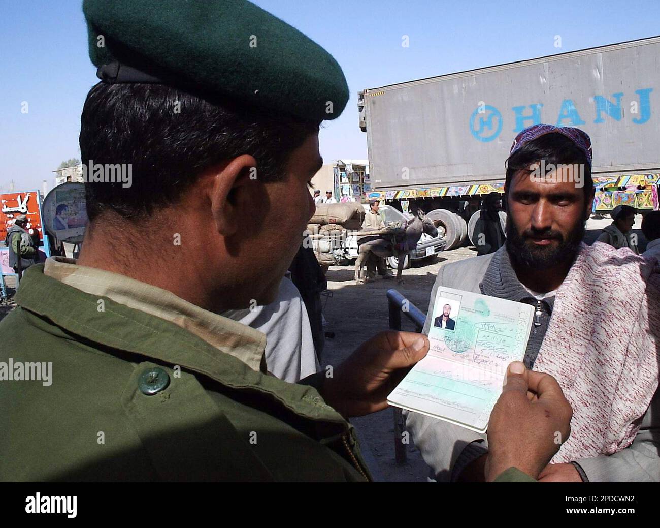 A Pakistani border guard checks the passport of an Afghan national ...