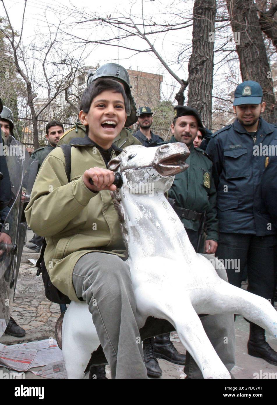 An Iranian school boy, plays with a toy horse at a park, in front of ...