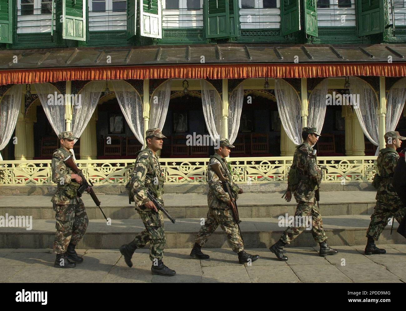 Nepali army soldiers walk past a building where photographs of former ...