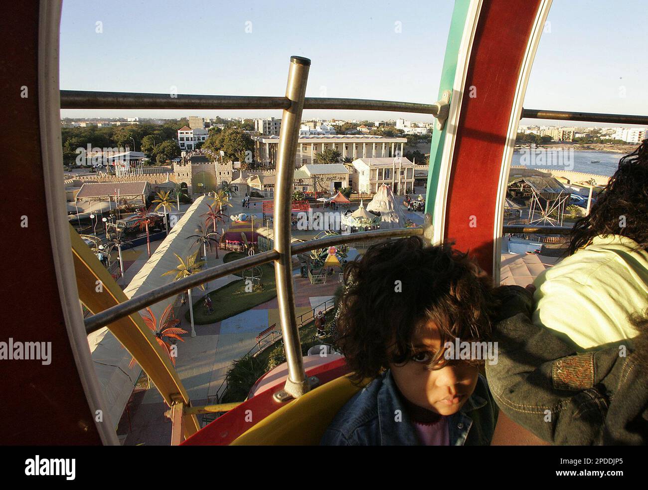 A child rides on a Ferris wheel, above a games park, Magic Land at ...