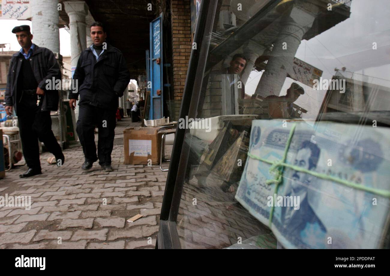 Two Iraqi policemen pass a souvenir vendor's display of old Iraqi ...