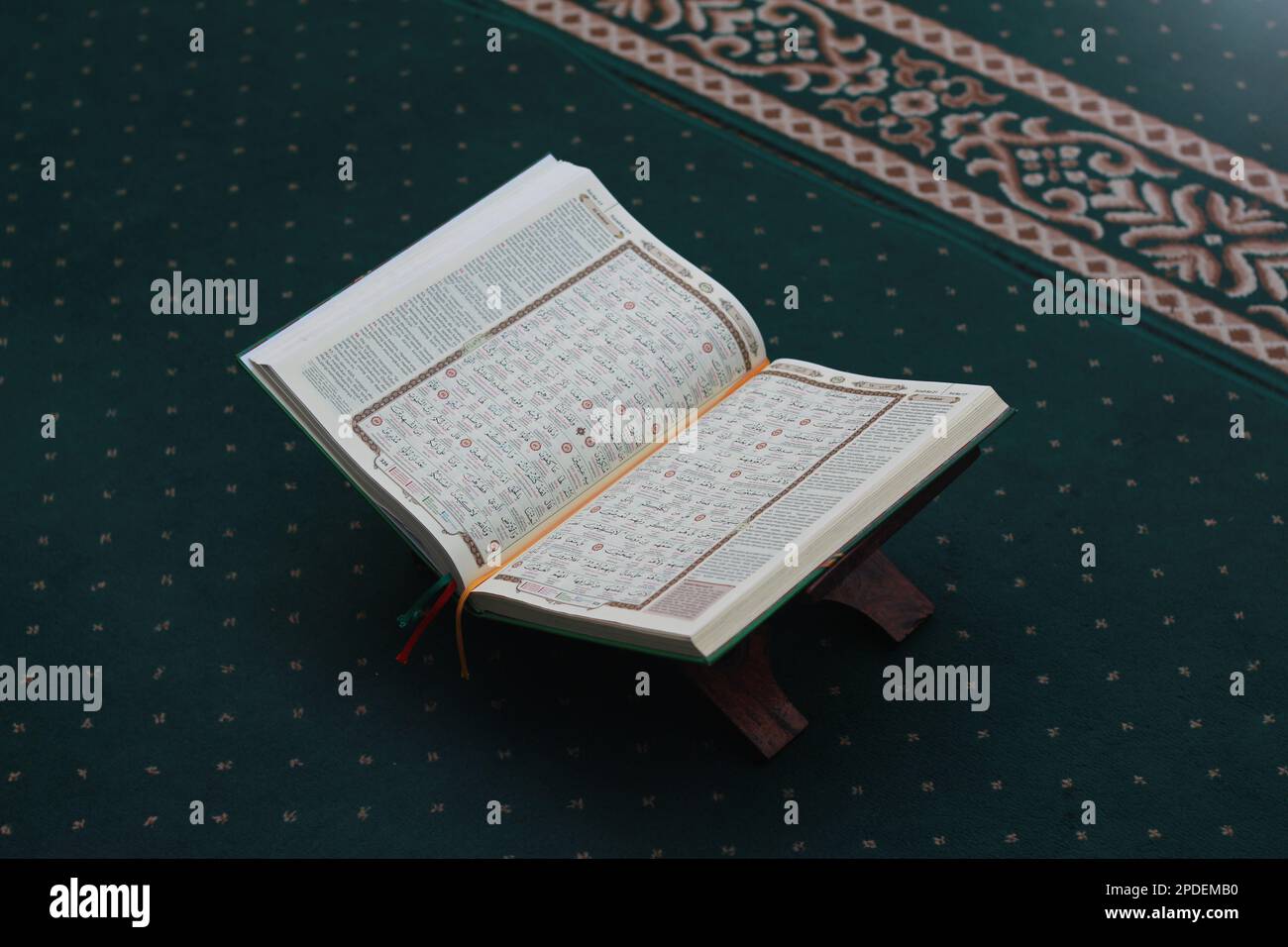 a close up of the holy book Al-Quran on a green prayer rug. Islamic ...