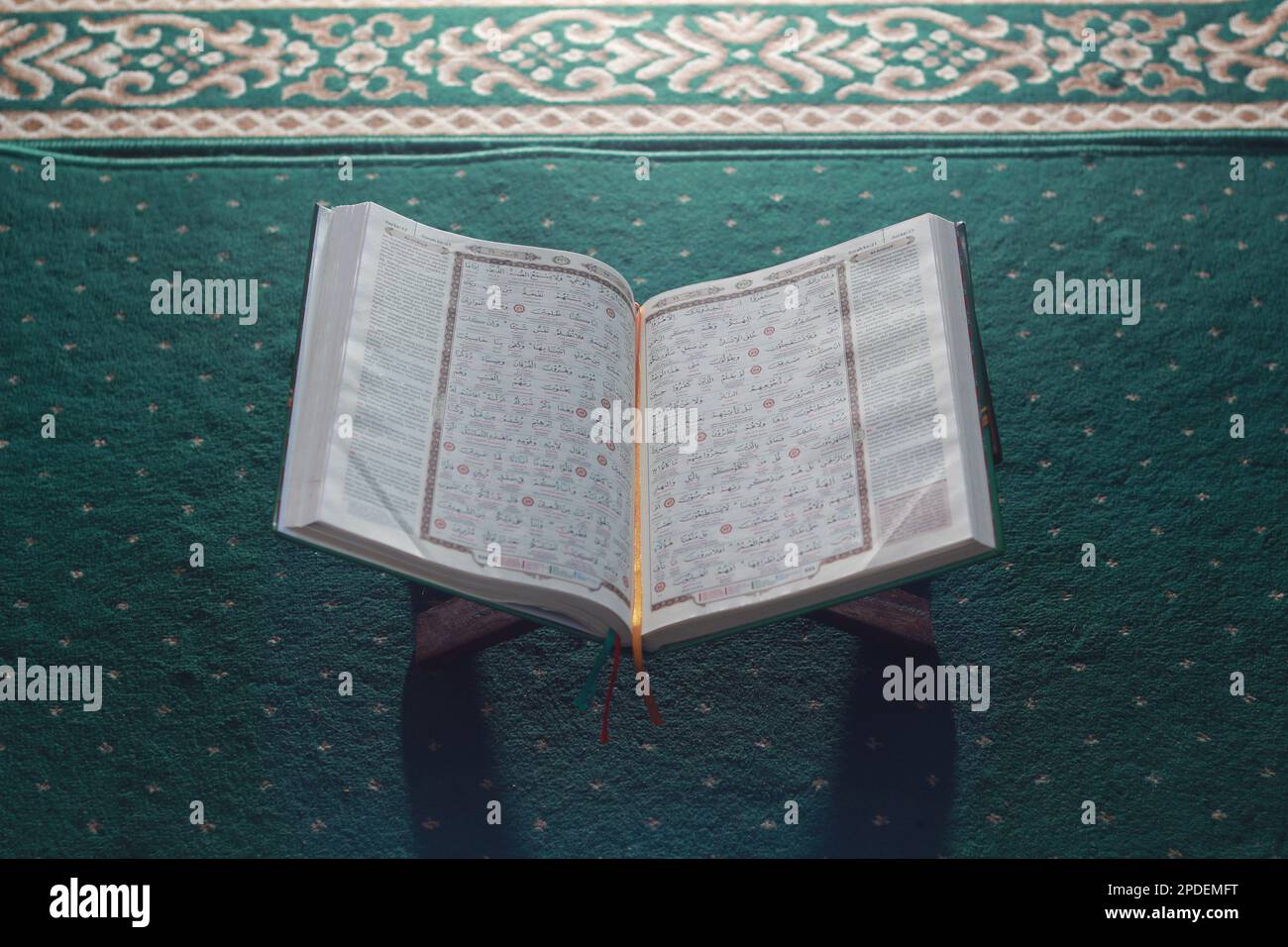a close up of the holy book Al-Quran on a green prayer rug. Islamic ...
