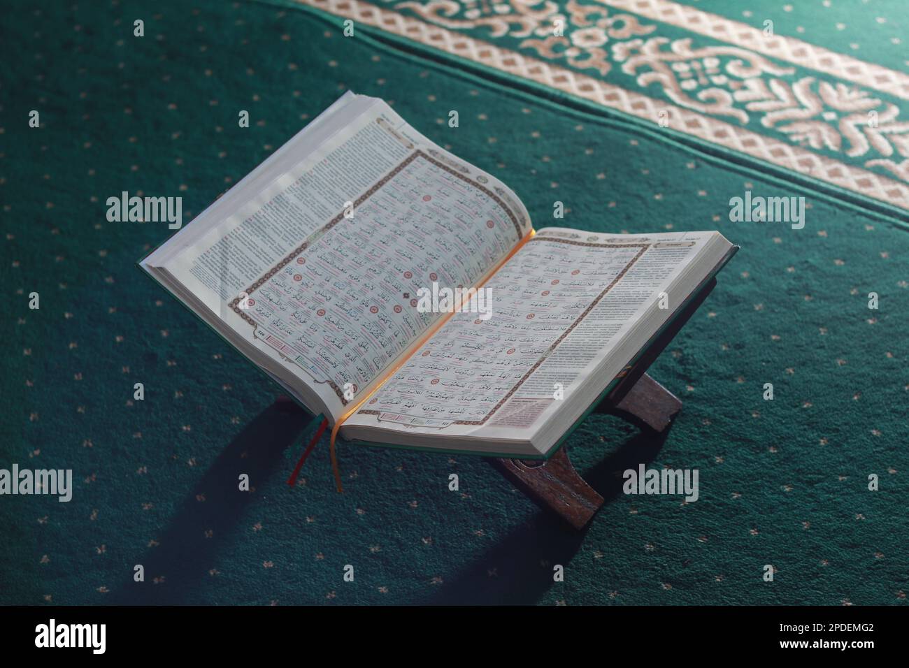 a close up of the holy book Al-Quran on a green prayer rug. Islamic ...