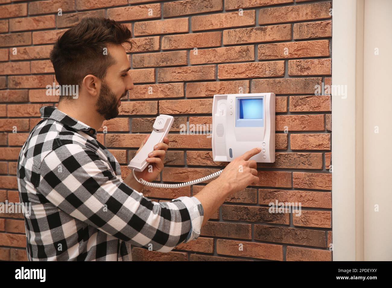 Man pressing button on intercom panel indoors Stock Photo - Alamy