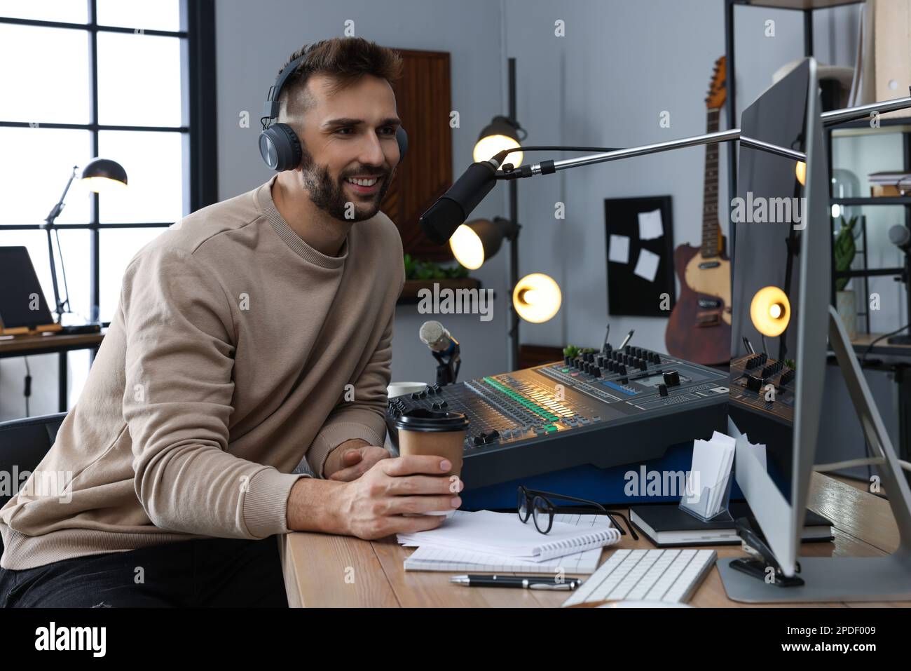 Man with cup of coffee working as radio host in modern studio Stock ...