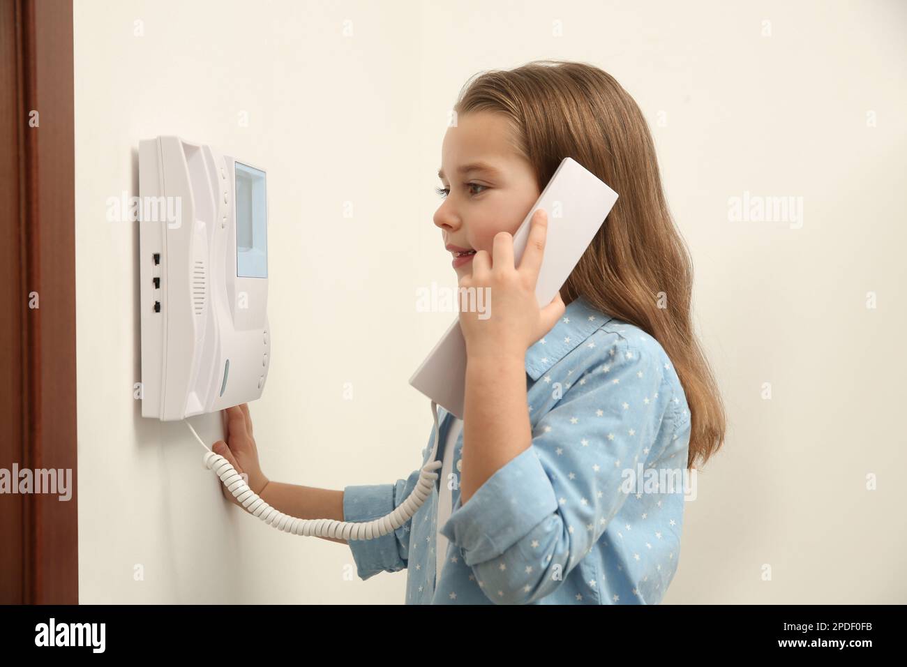 Cute little girl answering intercom call indoors Stock Photo - Alamy