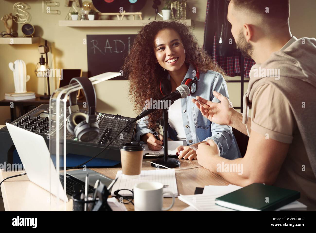 Young African American woman interviewing man in modern radio studio ...