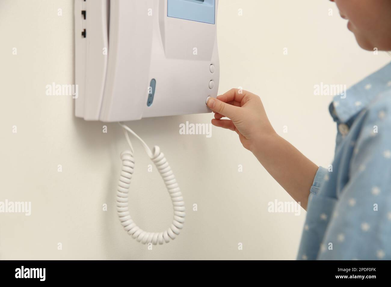 Cute little girl pressing button on intercom panel indoors, closeup ...