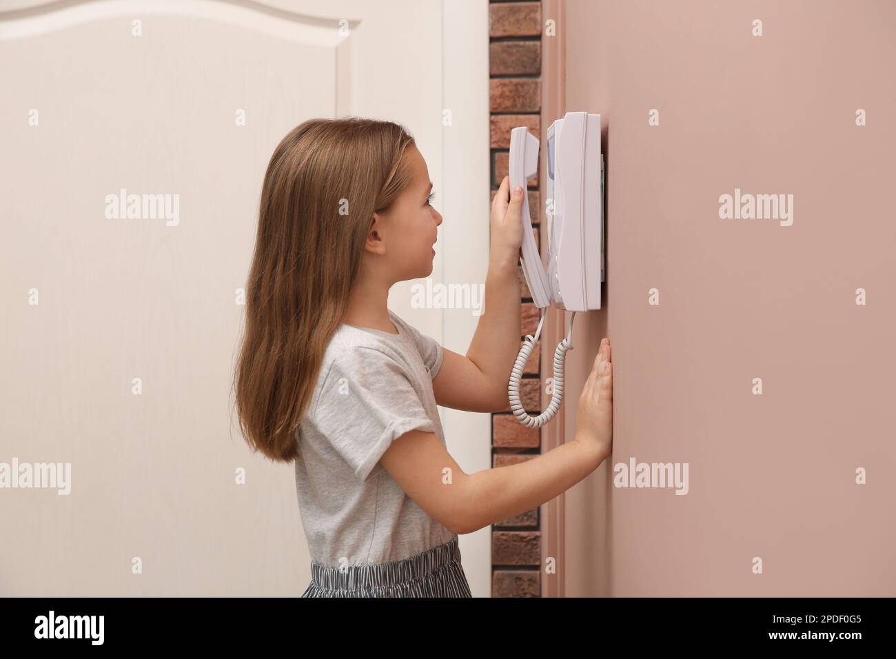 Cute little girl answering intercom call indoors Stock Photo - Alamy