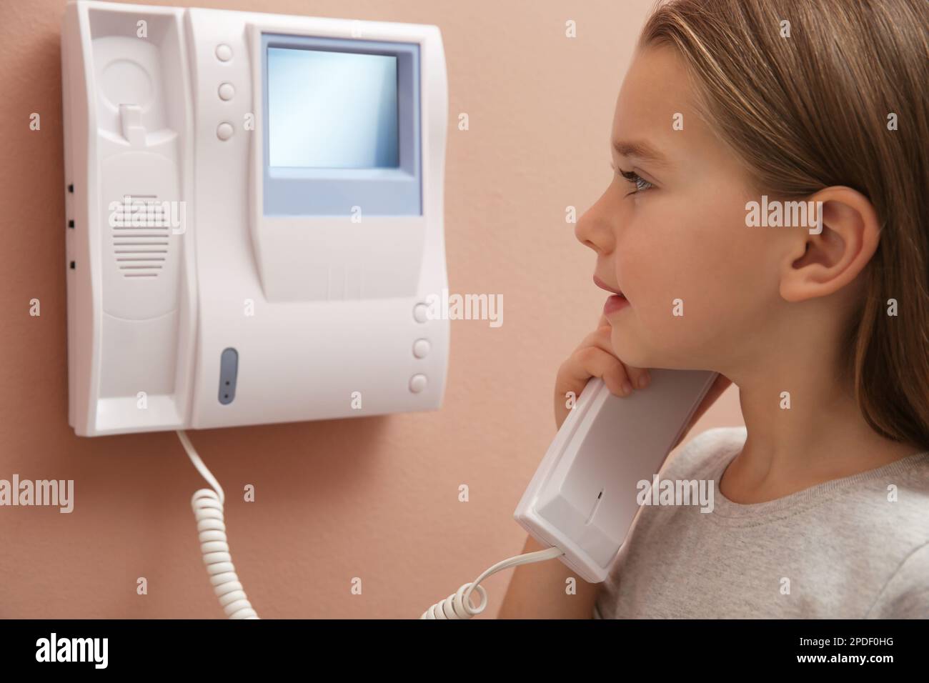 Cute little girl answering intercom call indoors Stock Photo - Alamy