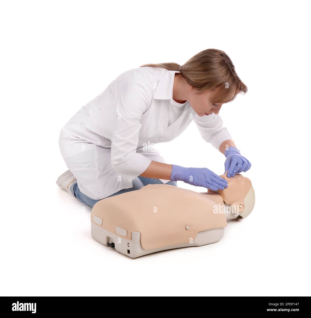 Doctor in uniform practicing first aid on mannequin against white ...