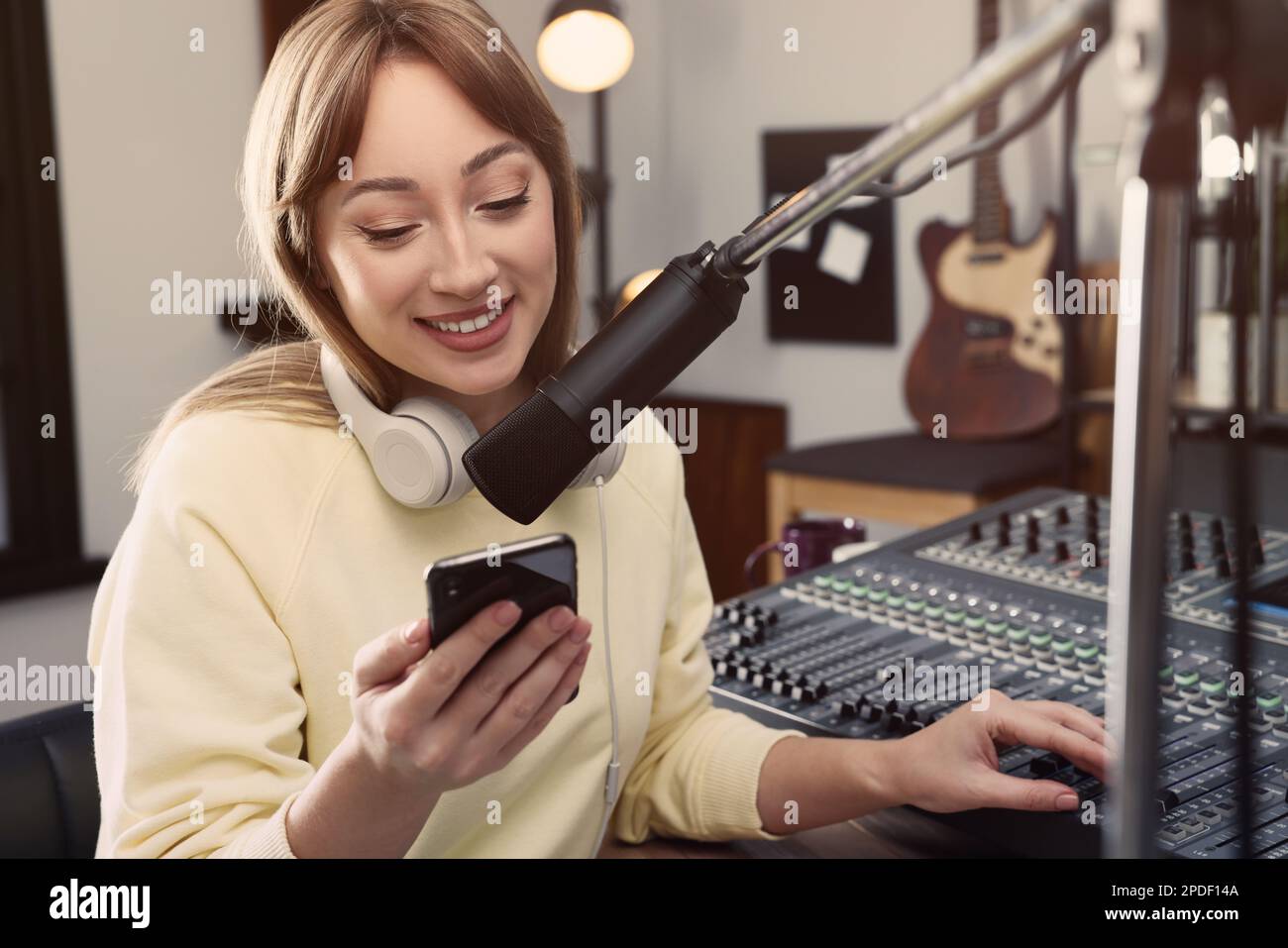 Woman with smartphone working as radio host in modern studio Stock ...