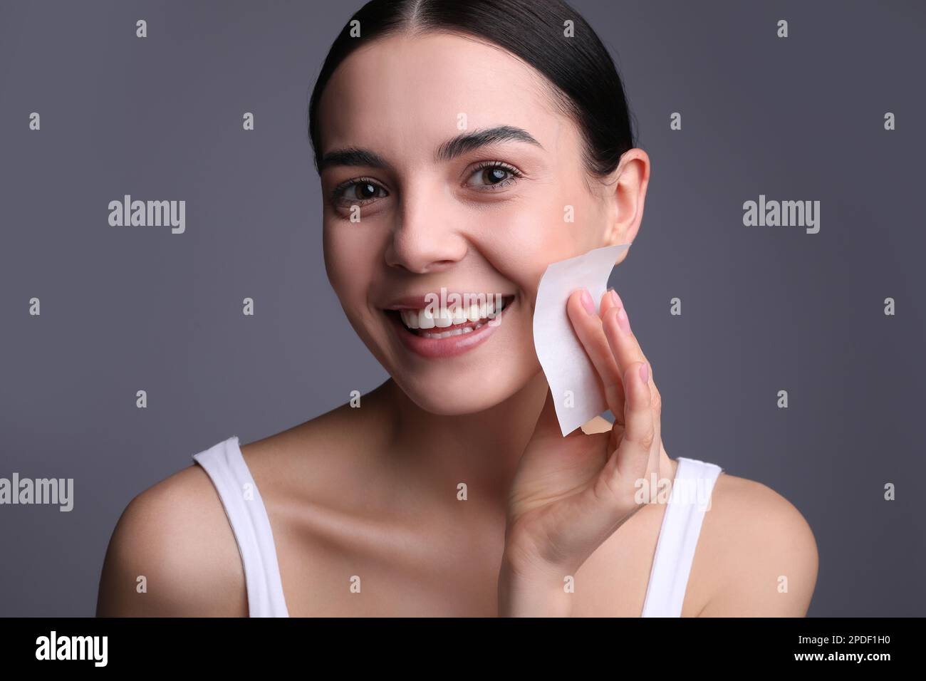 Beautiful woman using mattifying wipe on grey background Stock Photo ...
