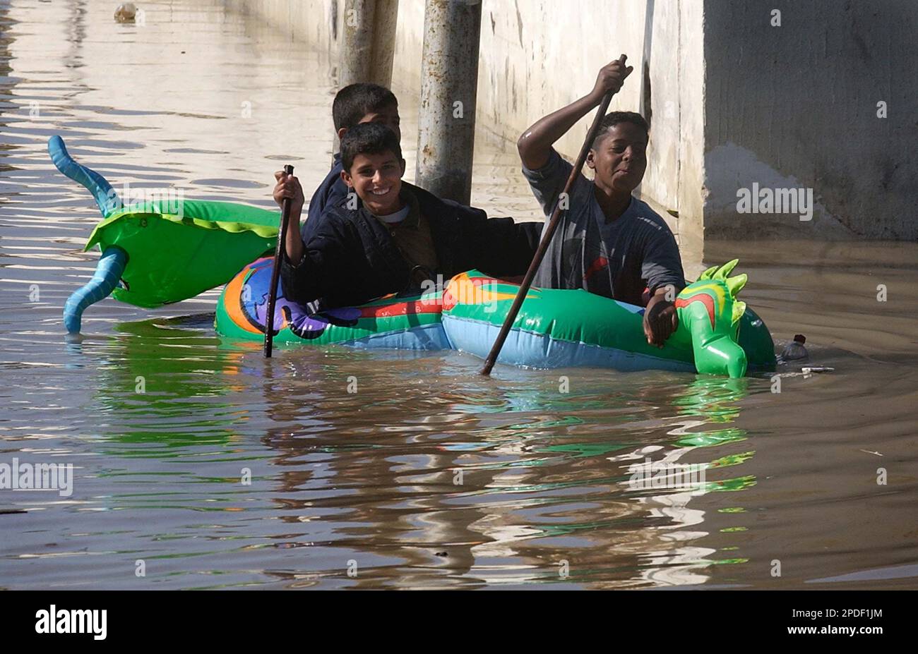 Iraqi boys float with an inflatable dragon raft in the floodwaters from ...