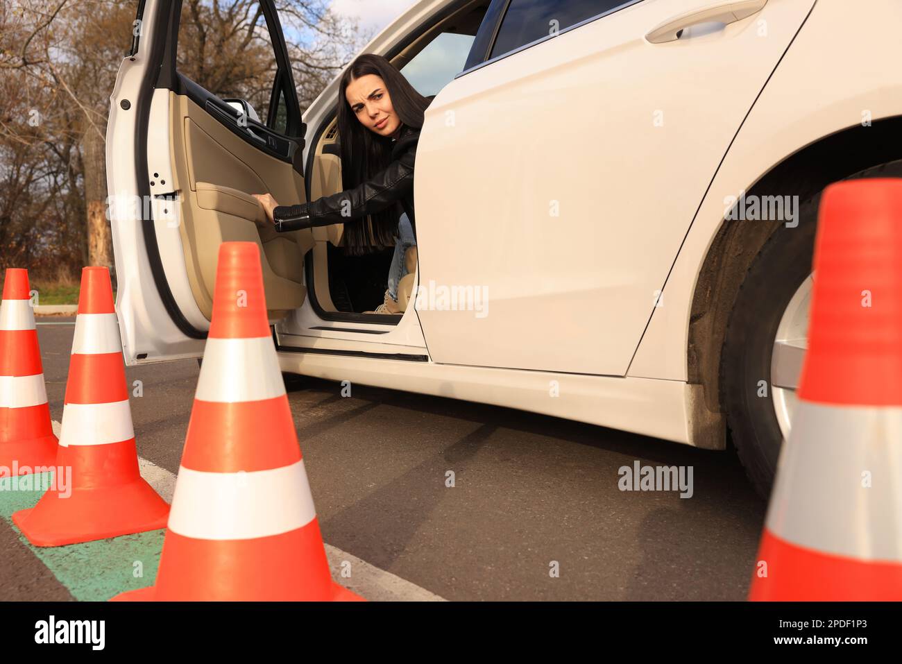 Young woman in car on test track with traffic cones, low angle view ...